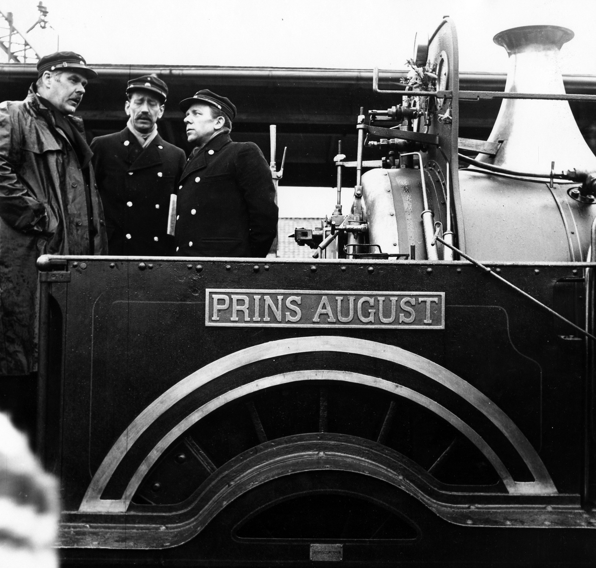 Tre män står uppe på loket 'Prins August'. Det historiska tåget ...