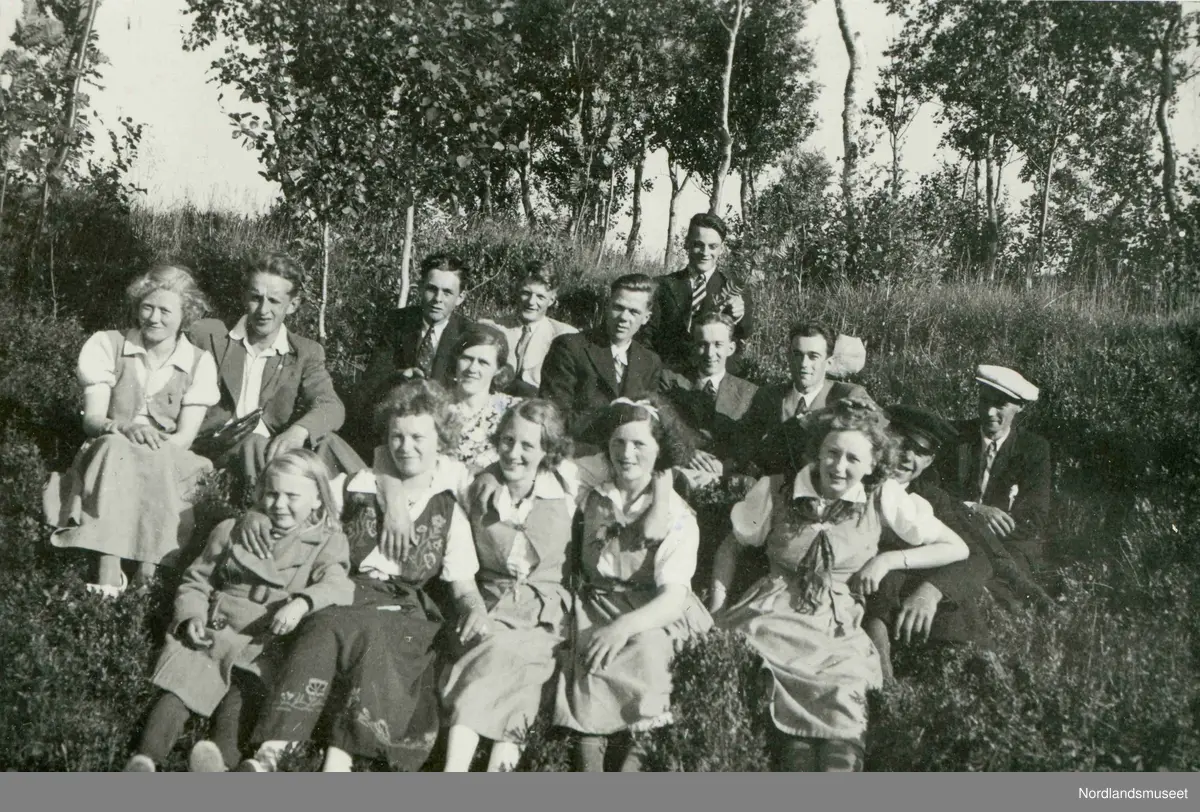 En flokk mennesker fra Nordskot i Leiranger som sitter i gresset. Noen ...