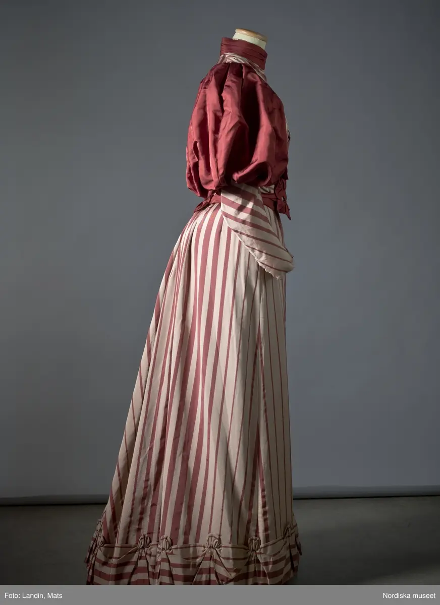 Klänning av ripssiden, röd- och beigerandig med vinröda puffärmar. 1890 ...