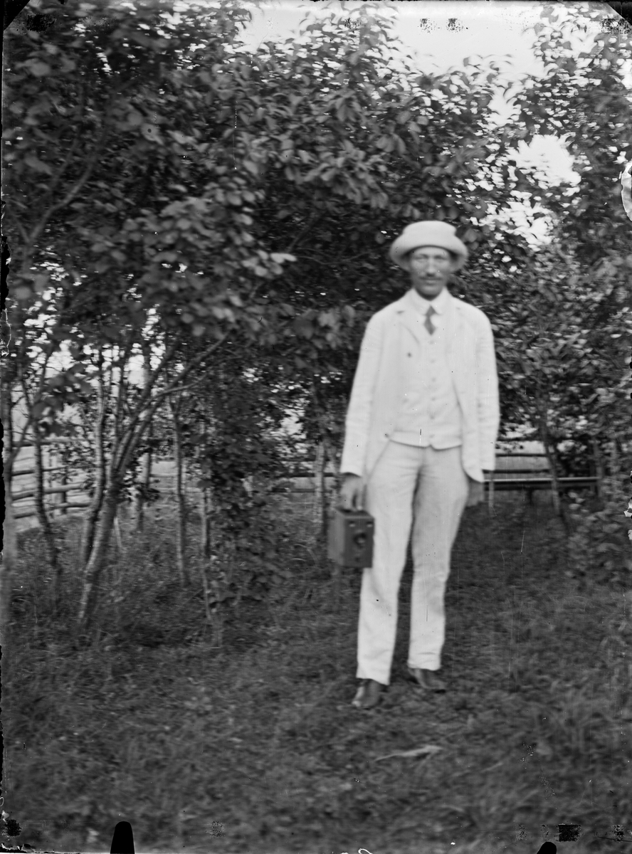 John Alinder med kamera i handen i trädgården, Sävasta, Altuna socken ...