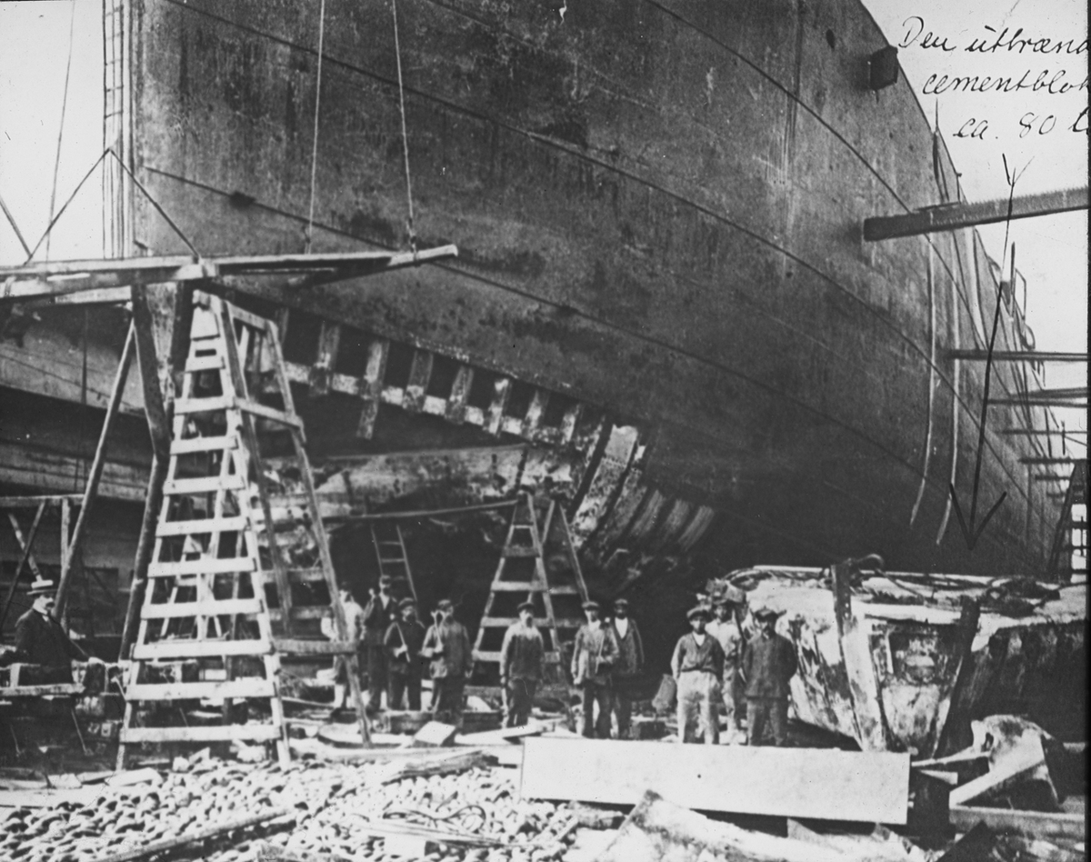 Skip i tørrdokk, stort hull i skroget. Dokkarbeidere stilt opp ved ...