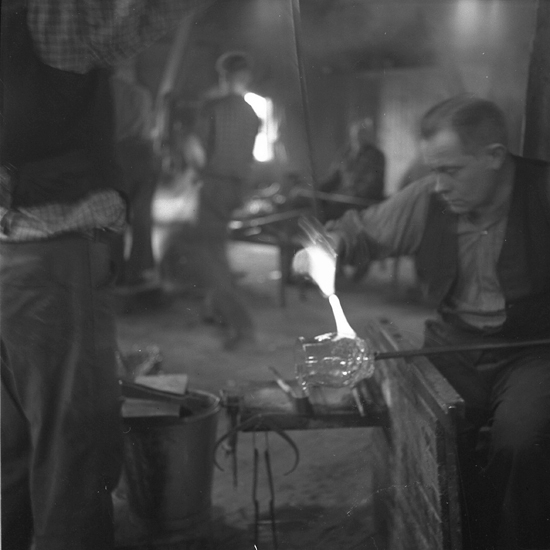 Mästare Harry Eriksson klipper på handtag på kanna, Reijmyre glasbruk ...