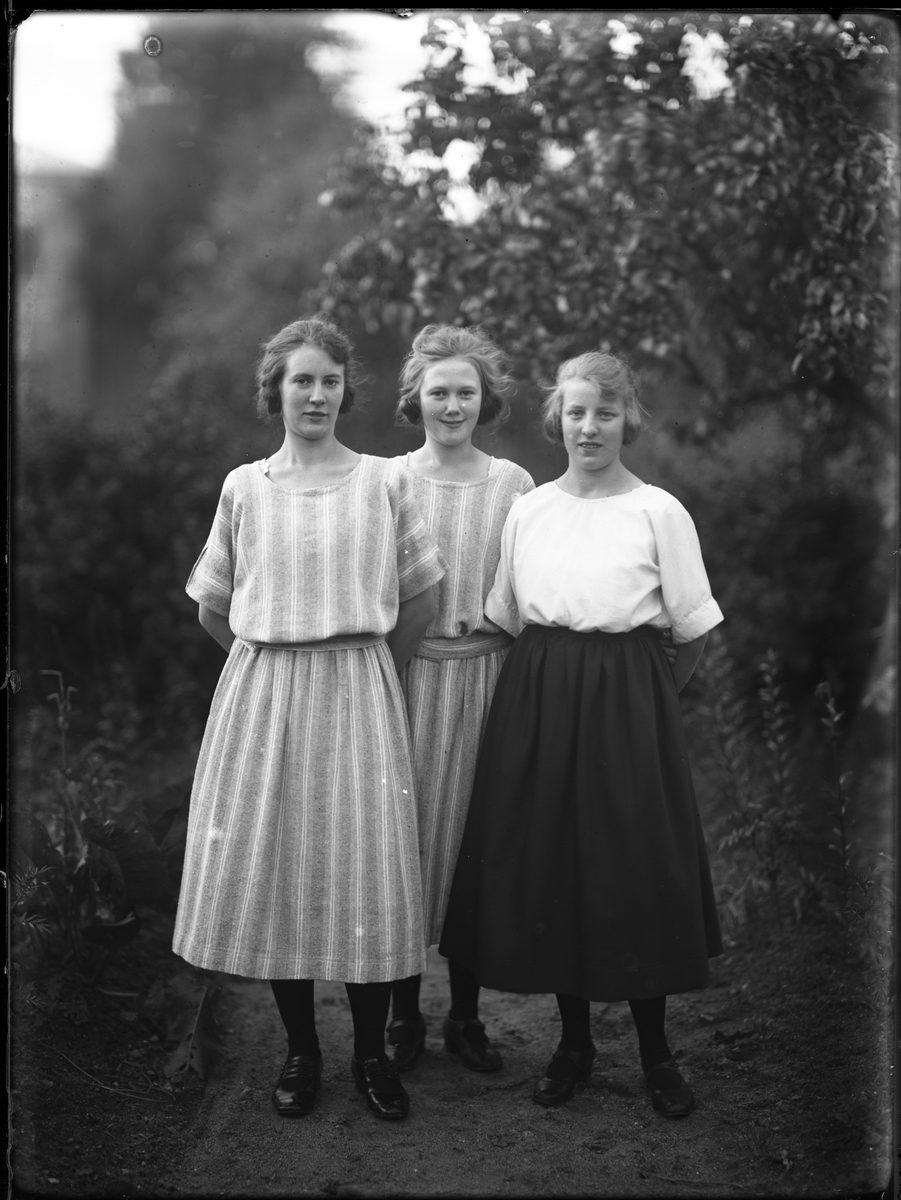 Lisa, Lilly och Agnes fotograferade stående i en trädgård. Lill och ...