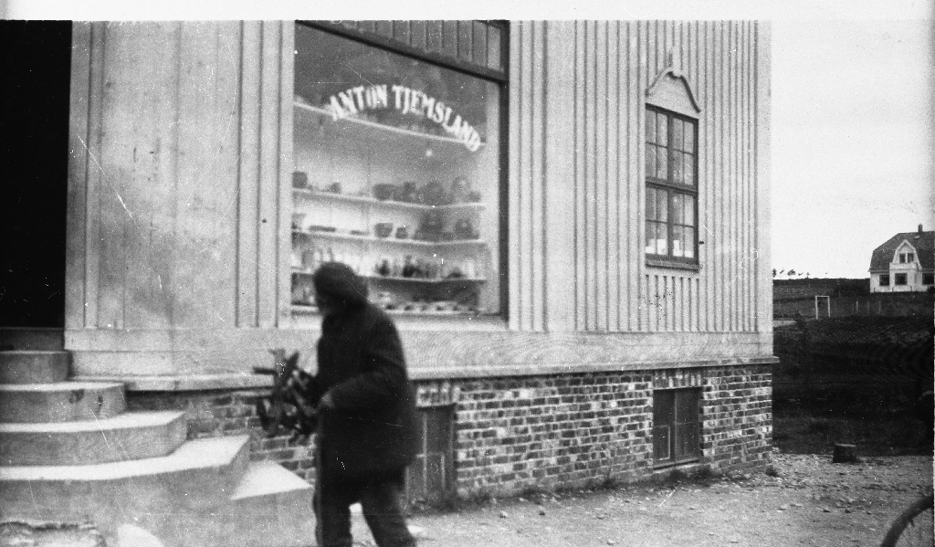 Pinn-Ola framfor forretninga til Anton Tjemsland. I bakgrunnen huset ...