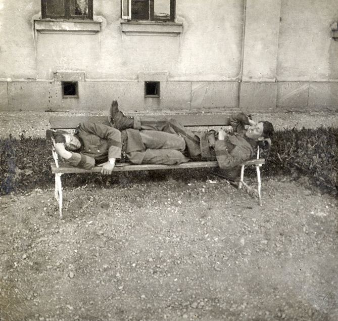 Foto av två soldater i uniform som vilar sig på en parksoffa. I ...